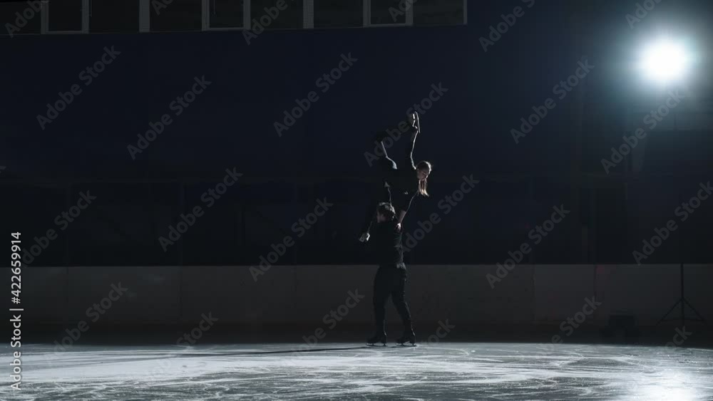 figure skating lift, pair of skaters are skating on ice rink, man is ...