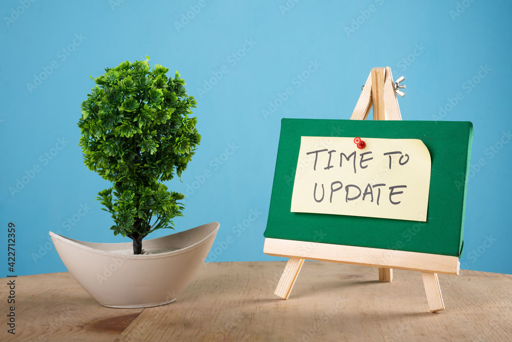 Time to update written on a sticky note on a mini green notice board ...