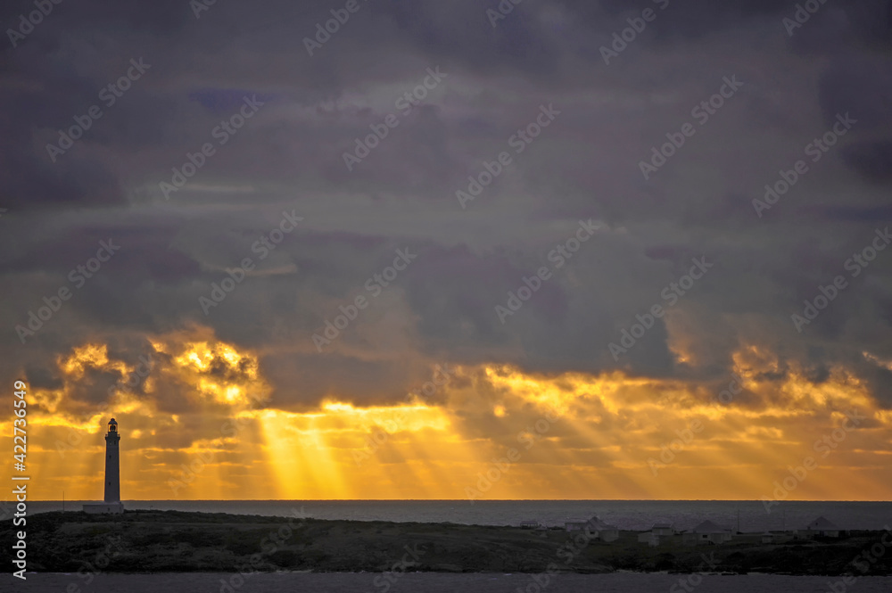 Yellow and grey sunset over the ocean with a light-house. The Indian ...