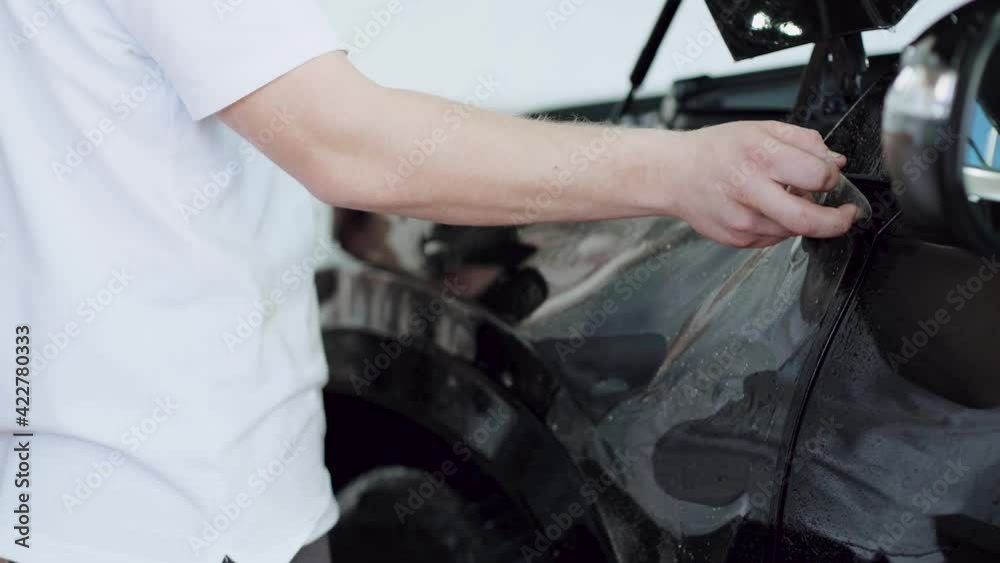 Film car protection male worker installing film to black color car in ...