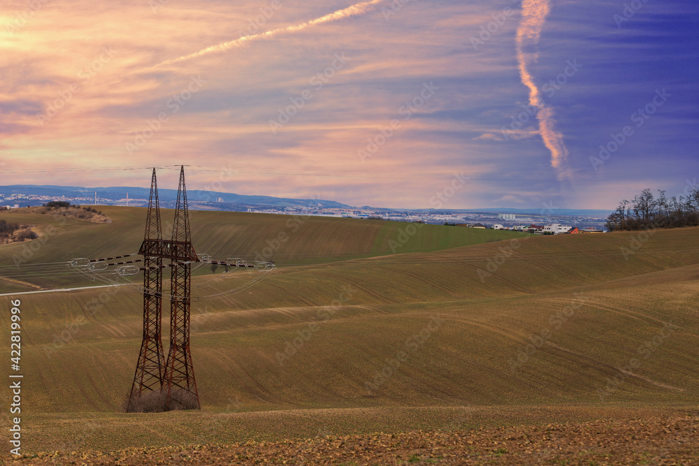 Spring landscape with field. High voltage poles stand in the middle. In ...