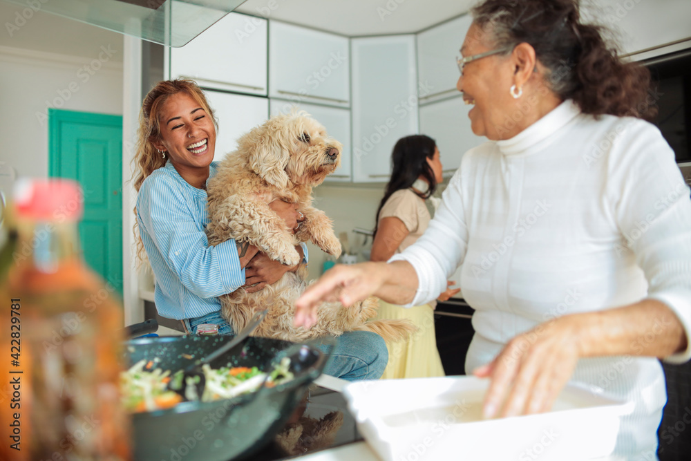 Filipino family cooking together at home - Young woman hugging her dog ...