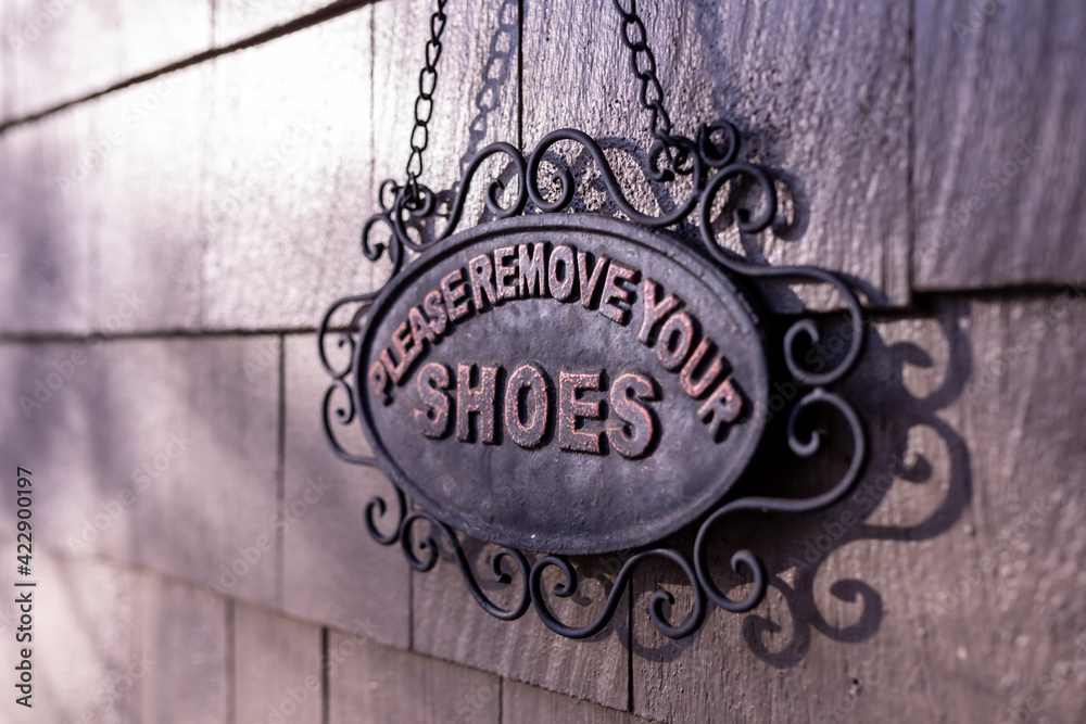 Decorative metal sign of oval shape on a chain hanging on a wall of a ...