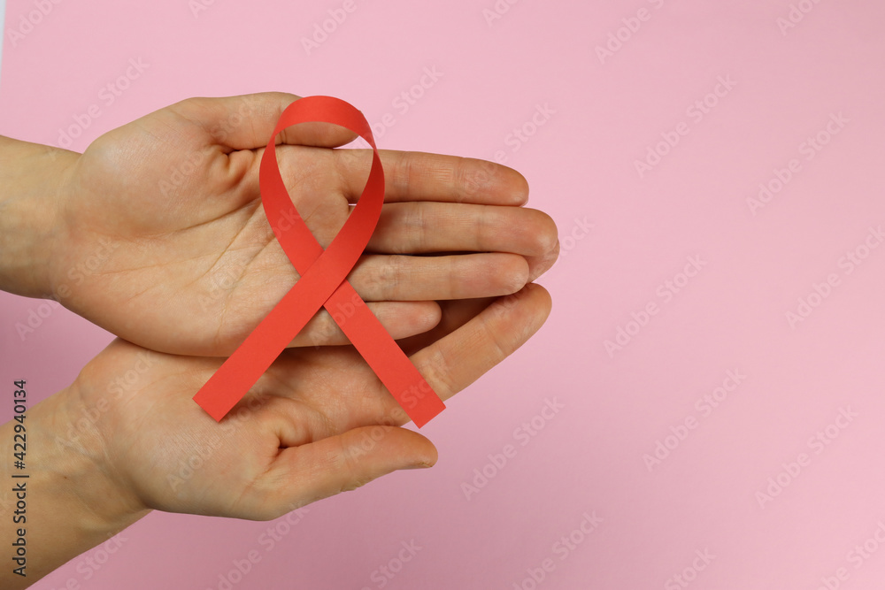 red ribbon in hand ,symbol of the fight against HIV, AIDS and cancer ...