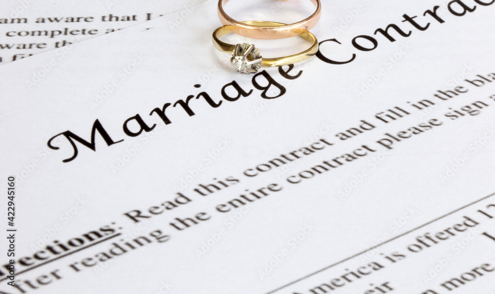 Marriage contract with two golden wedding rings and gold pen ...