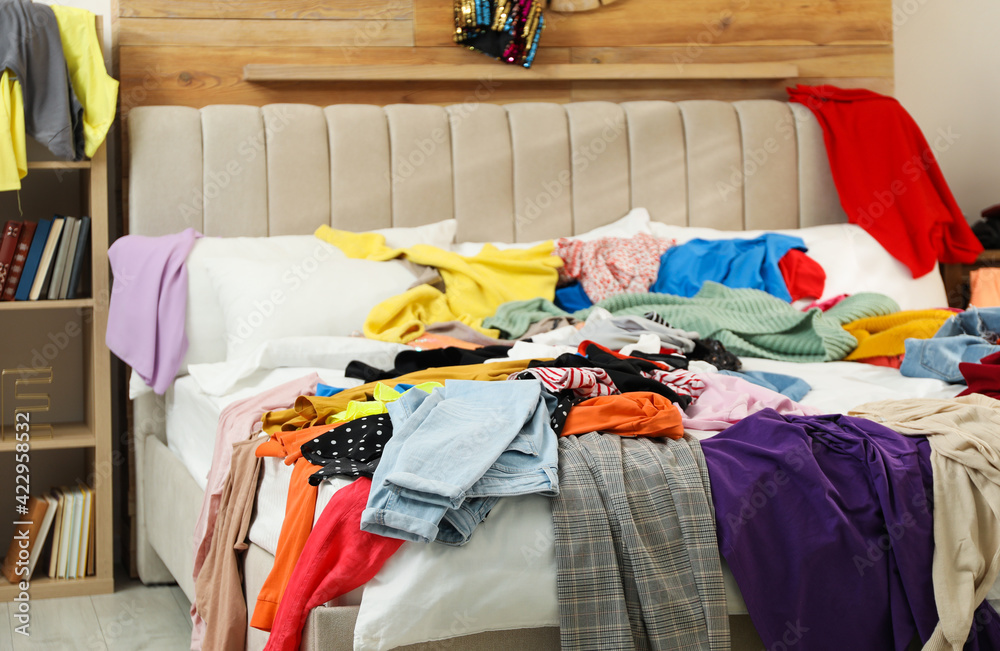Pile of clothes on bed in messy room. Fast fashion concept Stock Photo ...