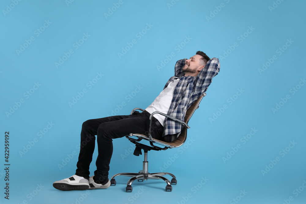 Handsome man relaxing in office chair on light blue background Stock ...