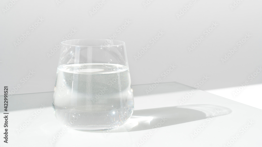 Glass of fresh pure water on white background with sunlight and deep ...