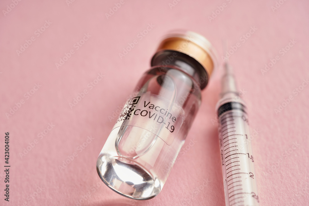 Covid 19 vaccine bottle and an injection syringe, on pink background ...
