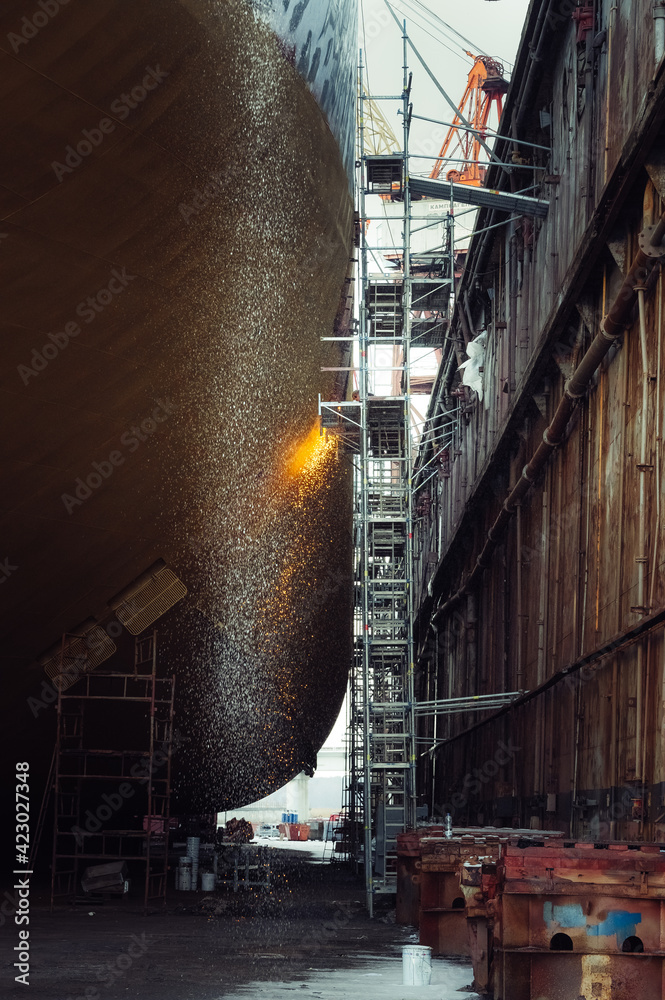 Man welding a carcass of ship standing on scaffold and wearing ...