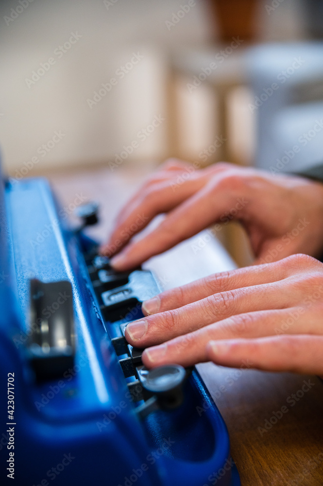 Crop anonymous visually impaired male typing on typewriter with tactile ...
