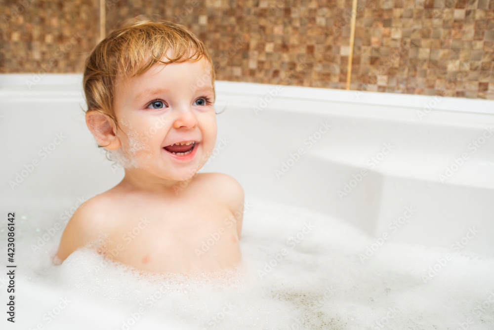Happy child is having fun by taking bath with foam in bathtub. Cute ...