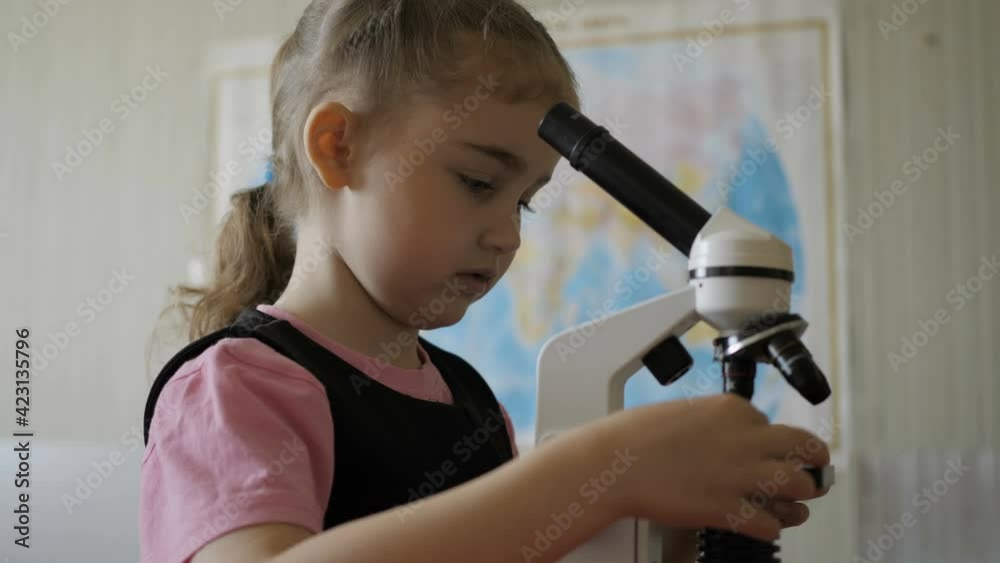 Little girl in science lab study samples under microscope. Schoolgirl ...