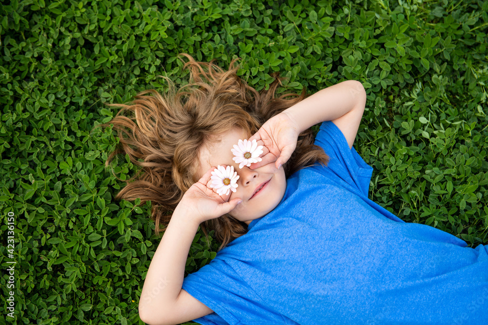 Happy child playing outdoors. Kid having fun in spring park lying on ...