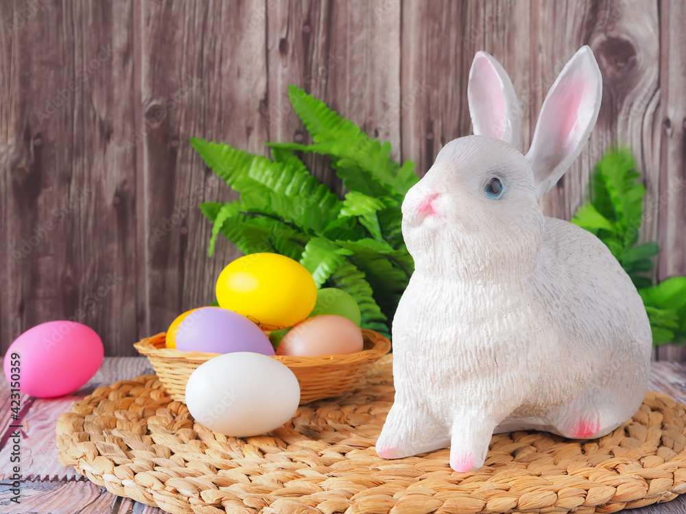 Easter bunny rabbit on rattan bamboo mat with multi colored eggs in ...
