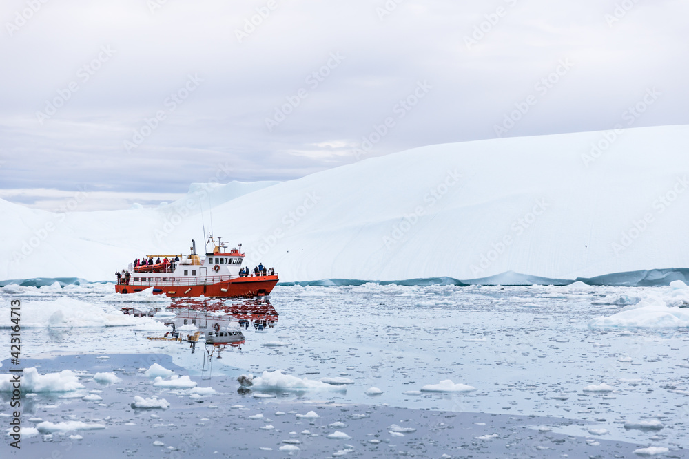 A red boat with people in swimming on the cold sea with many floating ...
