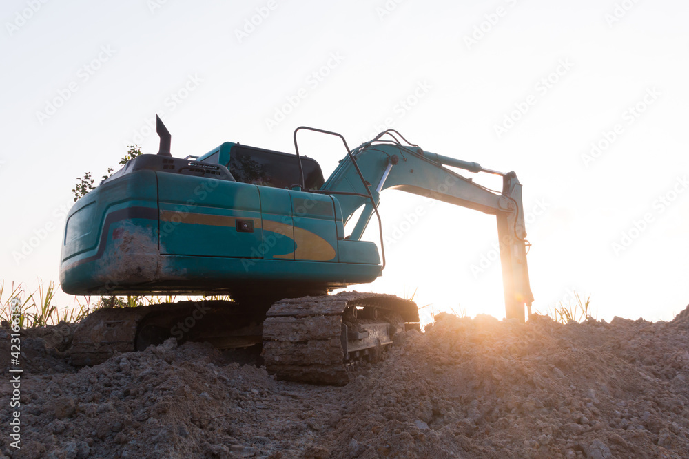 green excavator during earthmoving at construction site. Backhoe dig ...