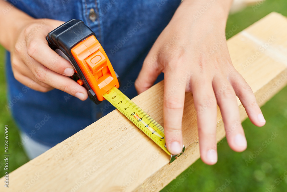 Hand of child with tape measure while measuring wood Stock Photo ...