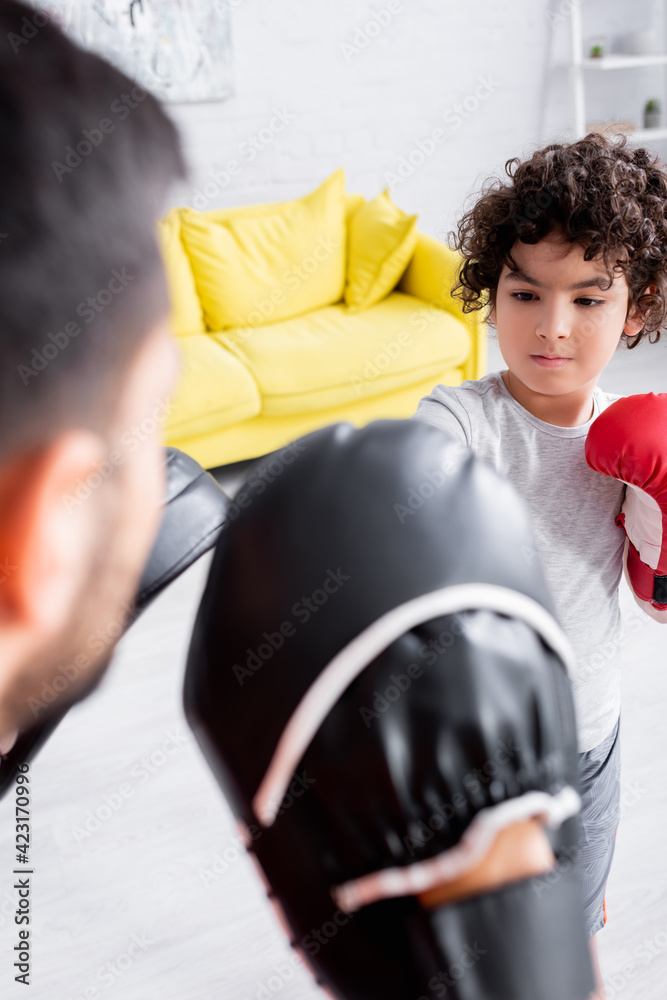 Muslim boy boxing during training with father in punch mitts on blurred ...