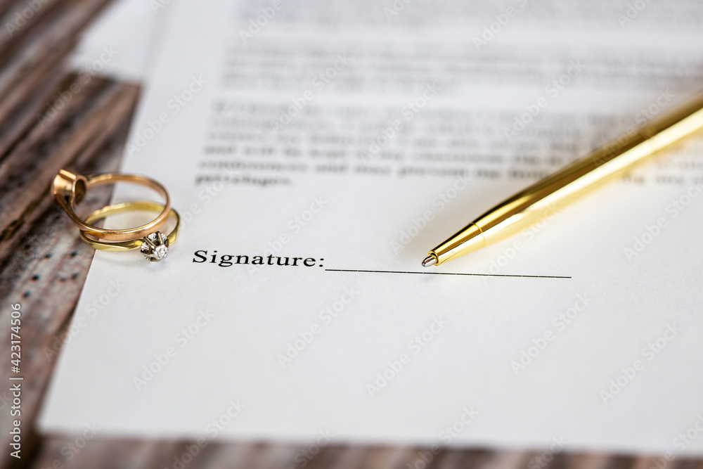 Marriage contract with two golden wedding rings and gold pen ...