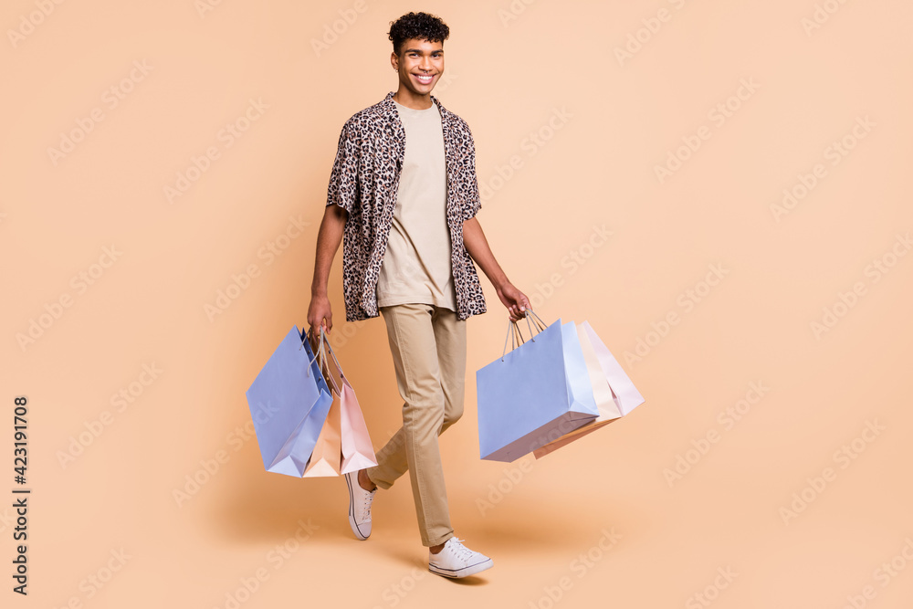 Full length portrait of positive dark skin man carry bags look camera ...