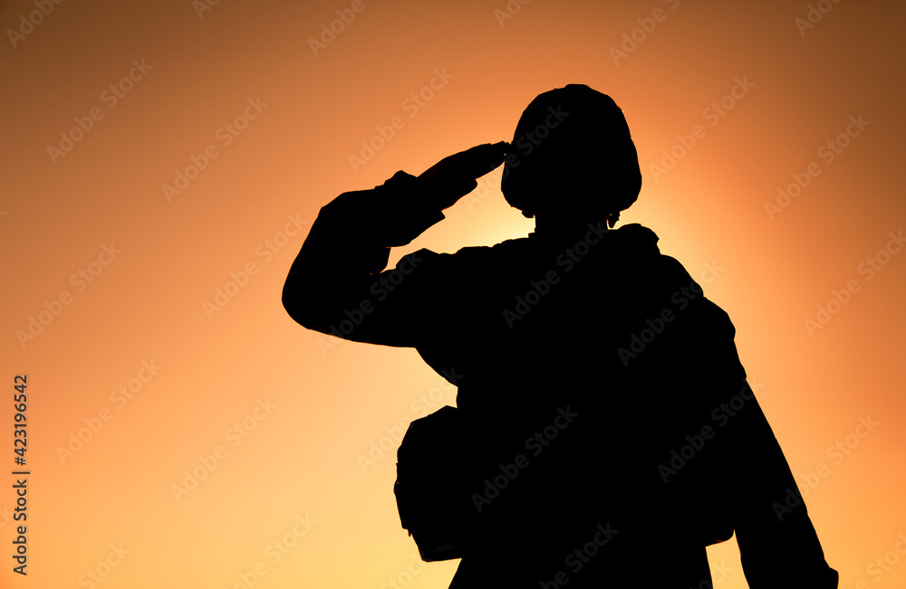Silhouette of soldier in combat helmet and ammunition saluting on ...