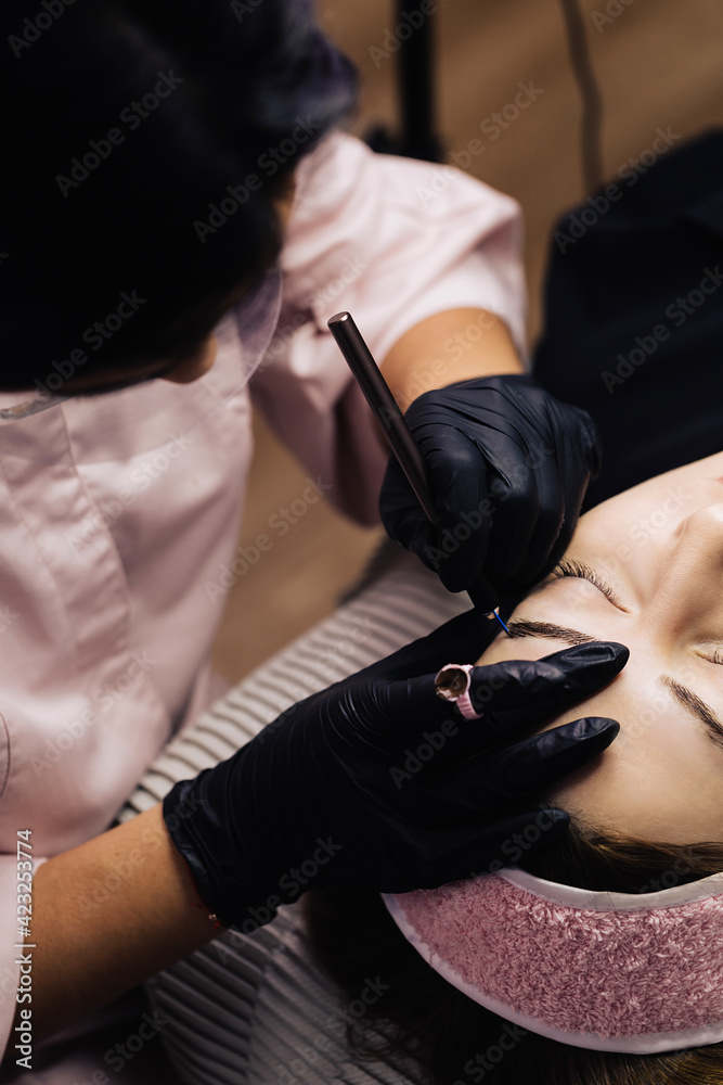 eyebrow microblading. A master in a transparent mask on his face and ...