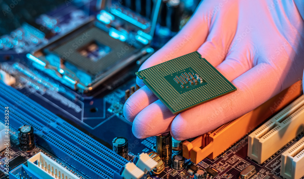 Engineer's gloved hand is holding the CPU chip on the background of the ...