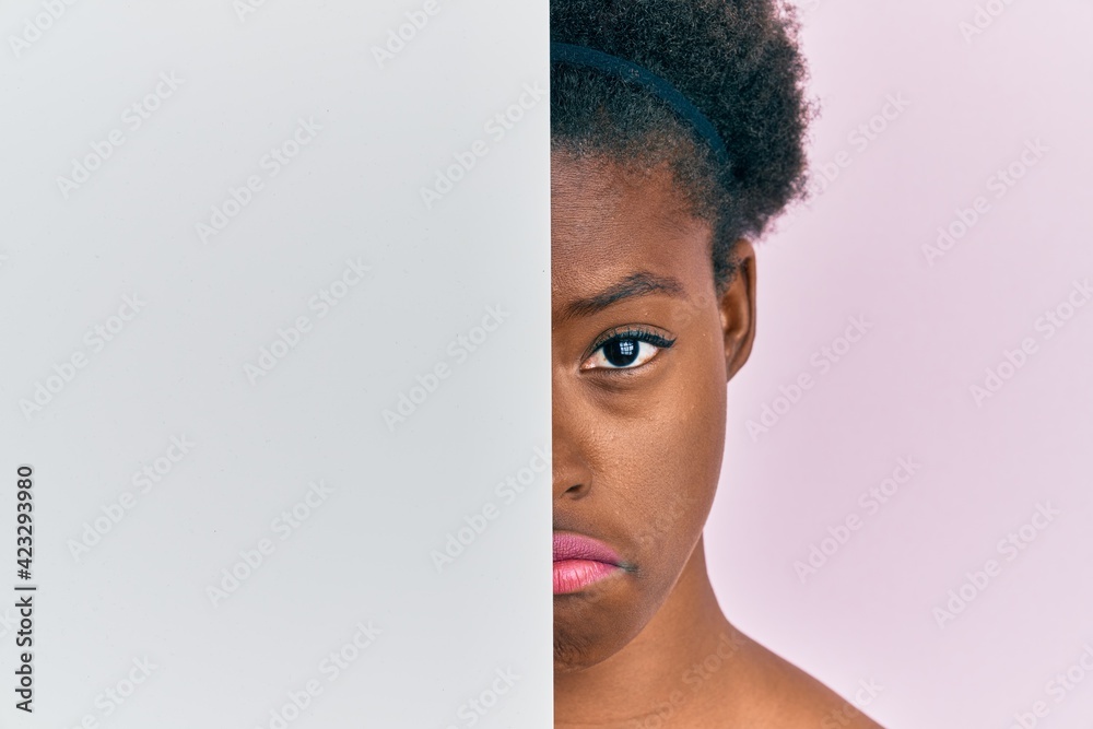 Young african american girl holding blank empty banner over half face depressed and worry for ...