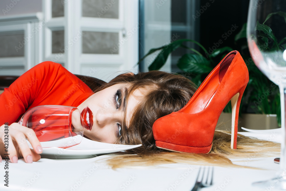 Elegant glamour young drunk woman lying on table with glass and poored ...