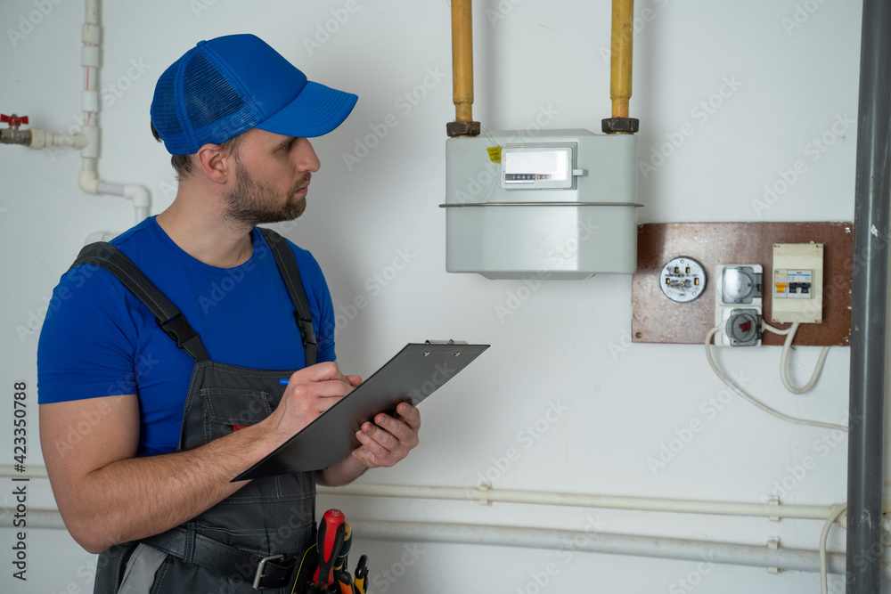 Man in uniform writes down the gas meter reading in a notebook. Stock ...