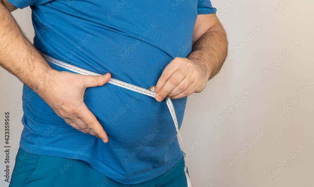 man measures the size of the abdomen with a centimeter measuring tape ...