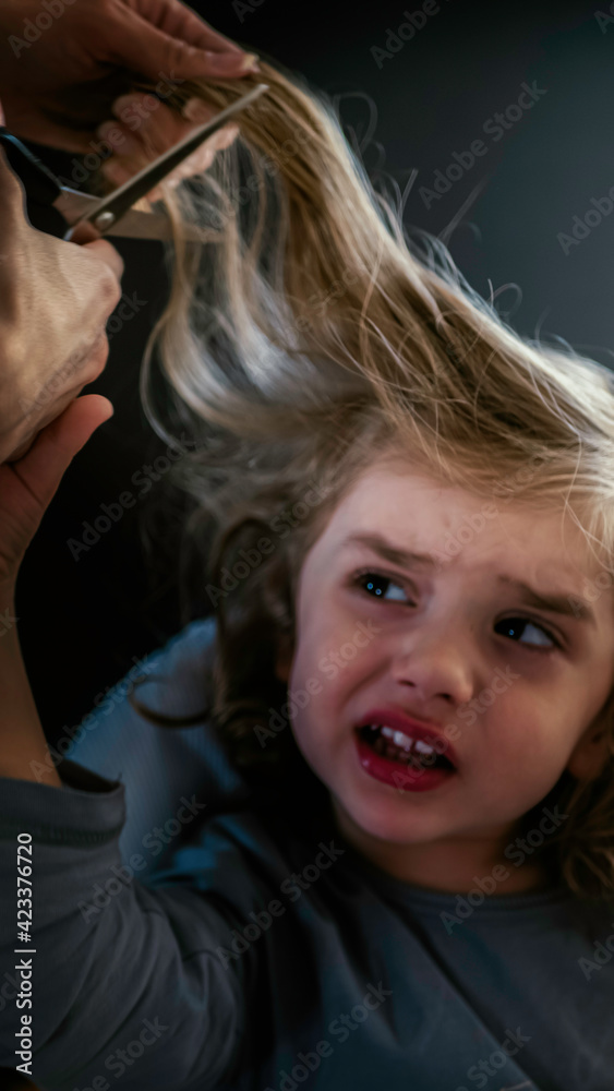 Little boy, toddler is afraid and doesn't want to cut his hair. A baby ...