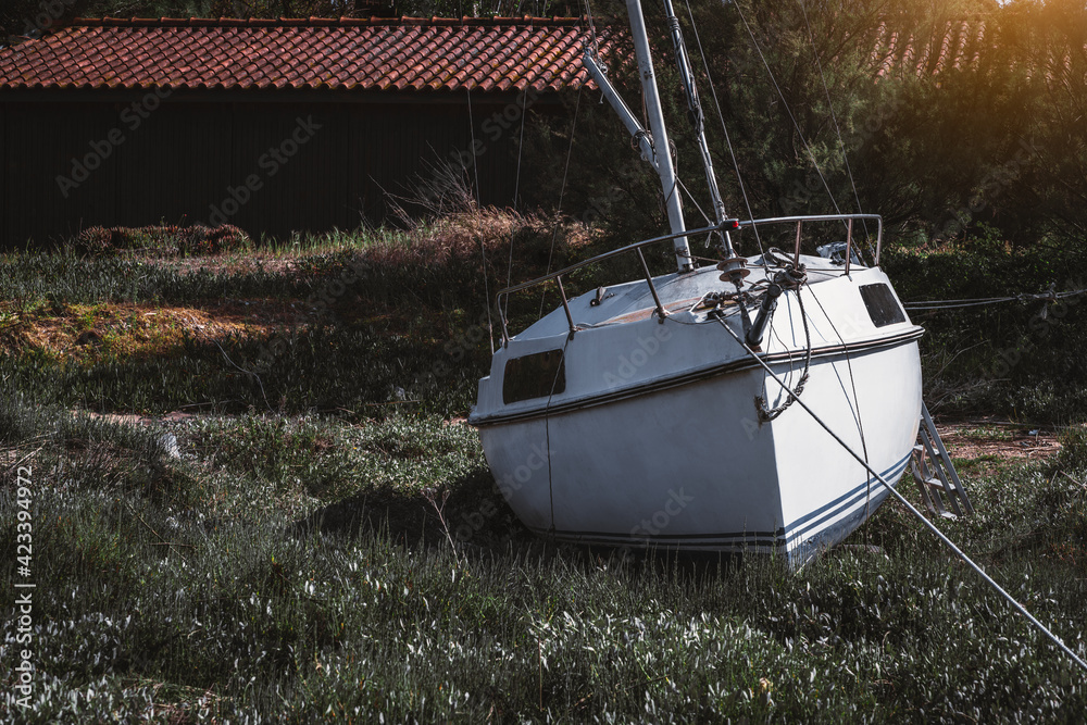 View of an old tilted sailboat with a bare mast without a sail, on its ...