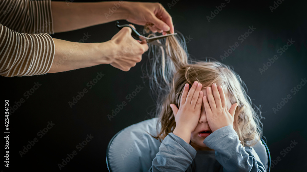 Little boy, toddler is afraid and doesn't want to cut his hair. A baby ...