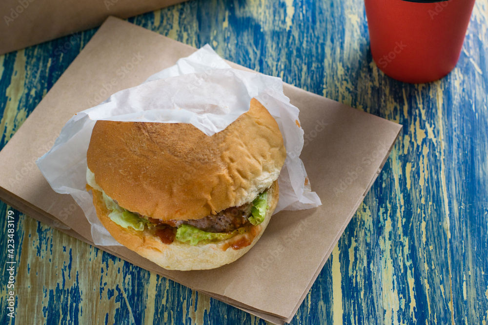 Burger with beef cutlet, sauce, salad and coffee to go in a paper cup ...