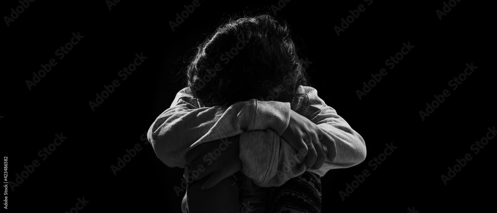 Little daughter sitting while holding her legs in sad emotion Stock ...