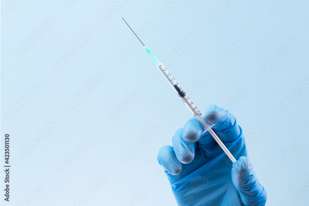 Doctor hand with nitrile glove and syringe with drop in needle ready ...