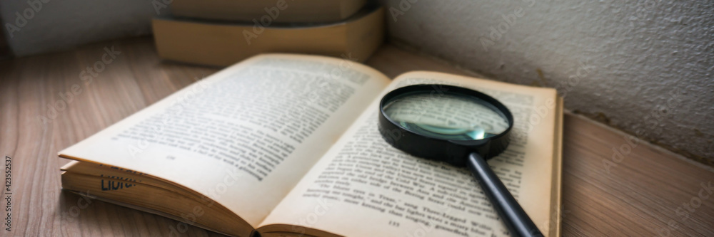 Books and a magnifier Research concept. Magnification glass over a ...
