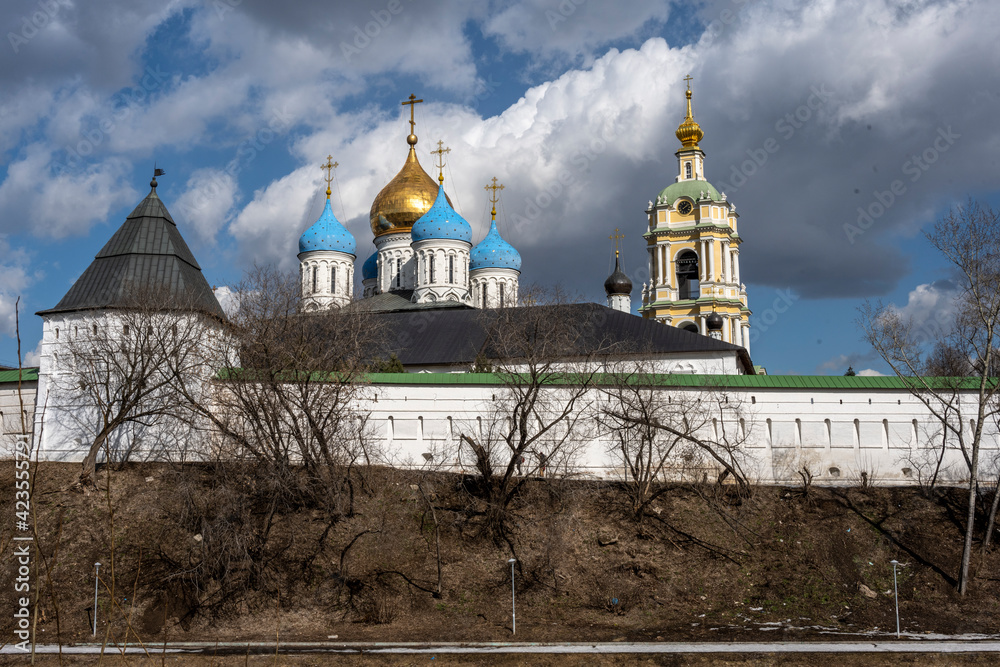old white stone monastery with golden domes on a sunny spring day ...