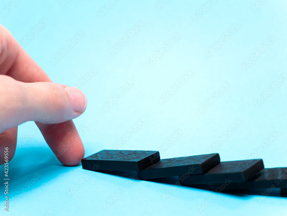 Domino effect, hand closeup. Finger knocked over a row of domino pieces ...