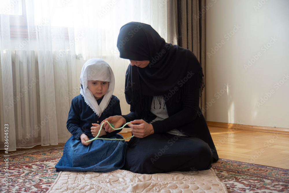 Little girl and her mother looking each other. Hijab muslim woman and ...