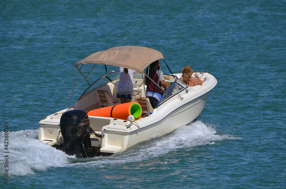 Motor boat powered by a single outboard engine, outfitted with a Bimini ...