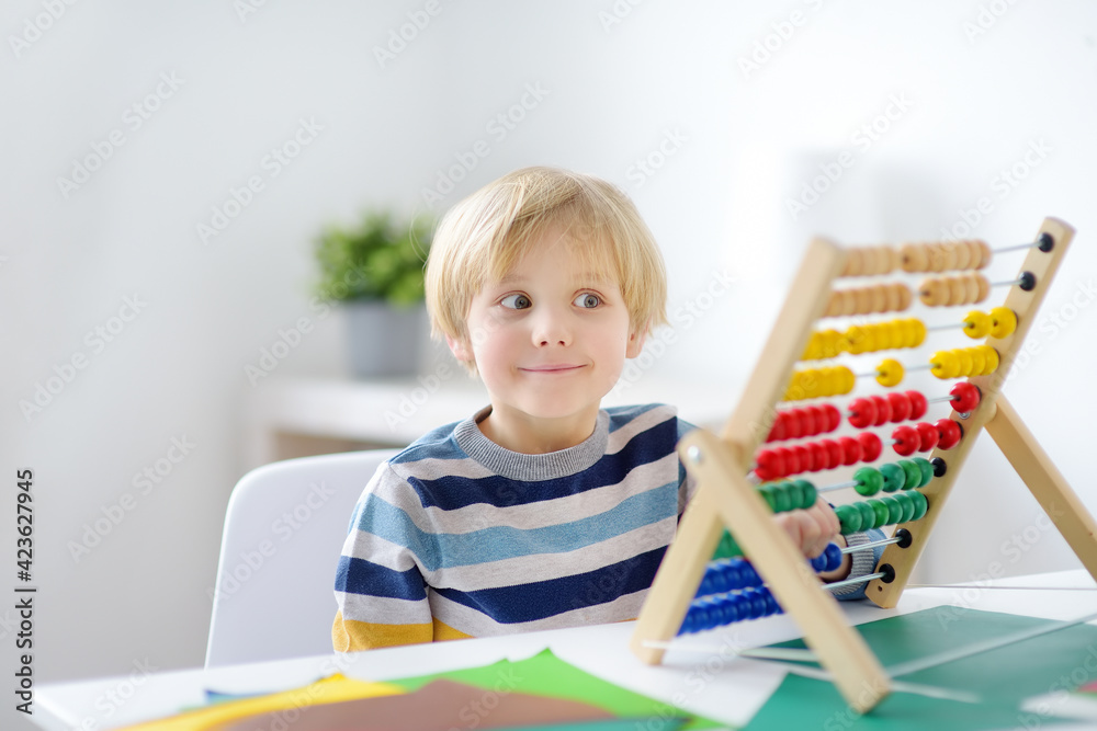 Elementary student boy doing homework at home. Child learning to count ...