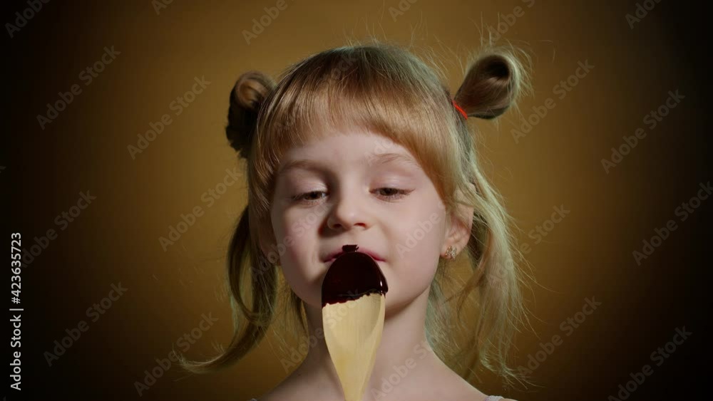 Close-up portrait of teen child kid eating, licking melted chocolate ...