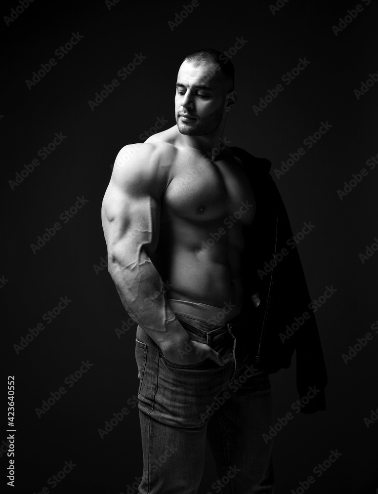 Black and white. Brutal muscular man, athlete, weightlifter stands in ...