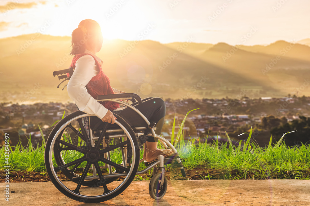 Disabled handicapped woman sitting on wheelchair sunset background ...