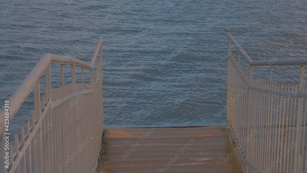 Stairs leading to the water of the bay. The splashing of water on the ...