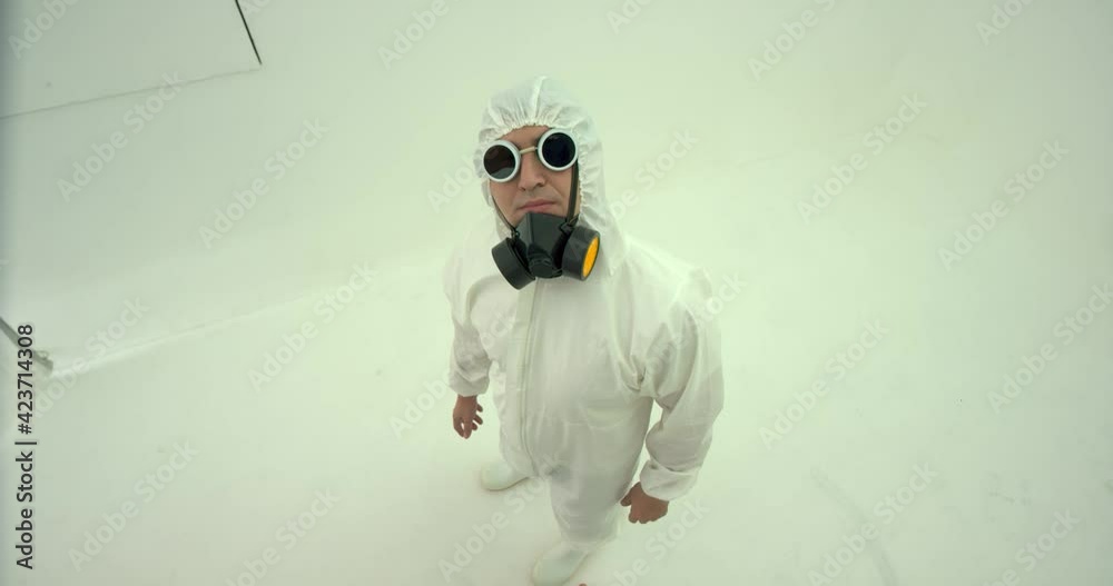 Man in protection suit and lowered gas mask walks into frame and stairs ...