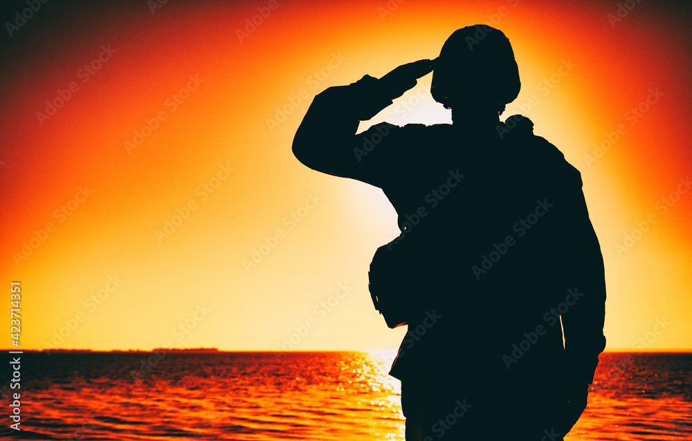 Silhouette of soldier in combat helmet and ammunition saluting on ...